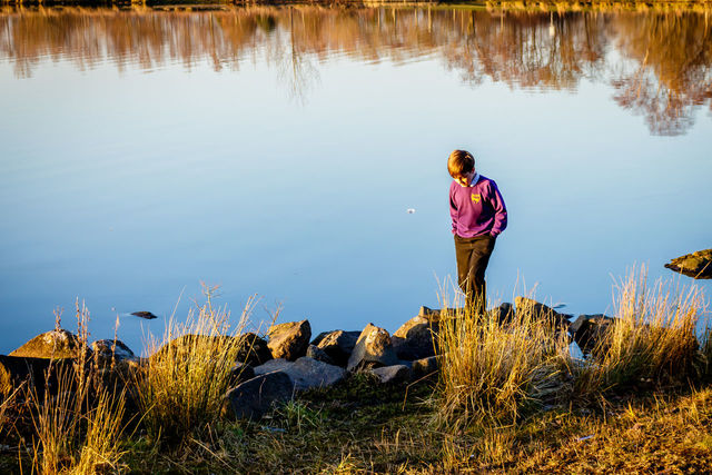 Boy looking down standing by lake | ID: 83286546