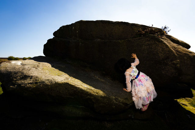 Rear view of girl hiding behind rock | ID: 122843430