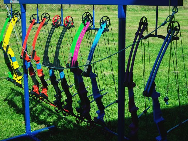 Colorful archery bow on stand at grassy field | ID: 72650796