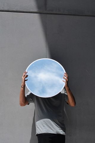 Man holding circle shaped mirror while | ID: 130489818