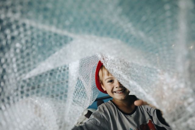 Portrait of boy playing with bubble wrap | ID: 128088532
