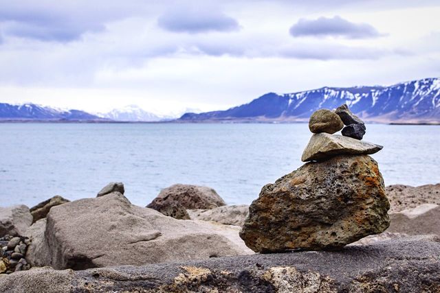 Stack of rocks at lakeshore against sky | ID: 54360873
