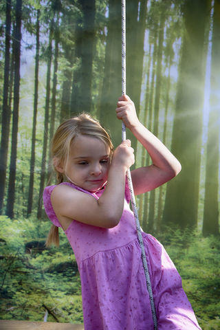 Girl hanging on rope against trees in forest | ID: 148367782