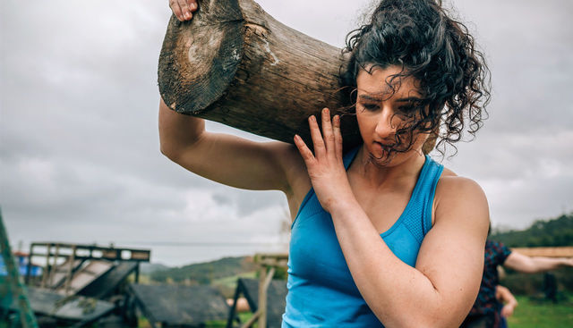 Woman carrying log on shoulder against sky | ID: 140156546
