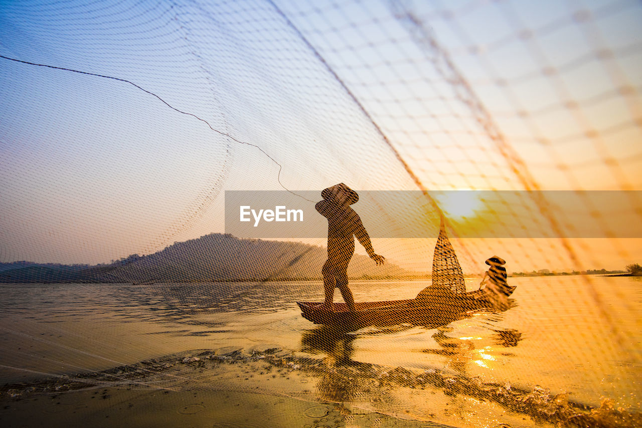 Man throwing fishing net in sea | ID: 141743269