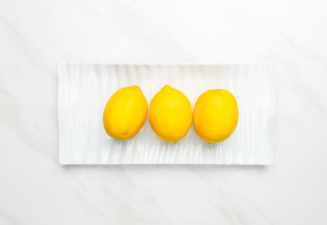 3 meyer lemons on a white plate from above | ID: 153989689