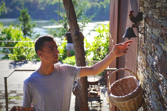 Young man ringing bell while standing by | ID: 144097860