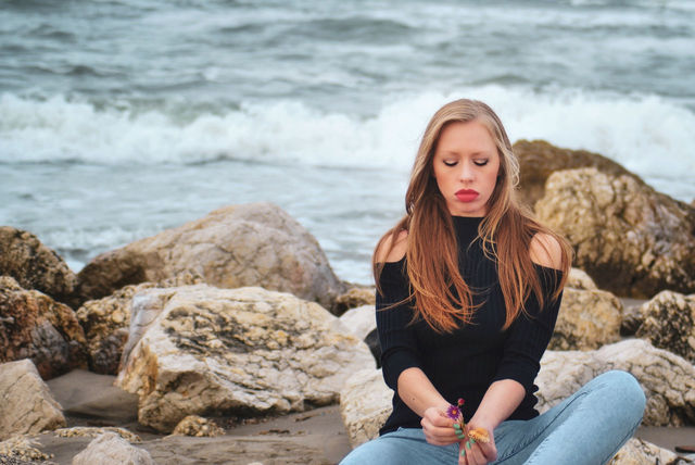Young woman sitting on rock at beach | ID: 160704574
