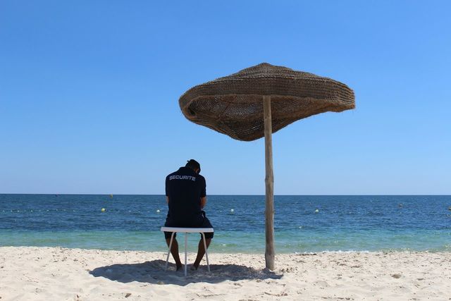 Rear view of lifeguard sitting under parasol | ID: 69145910