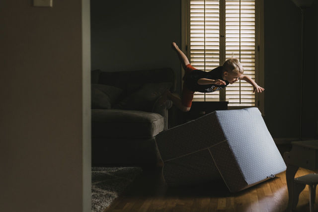 Boy jumping on chair at home | ID: 106436306