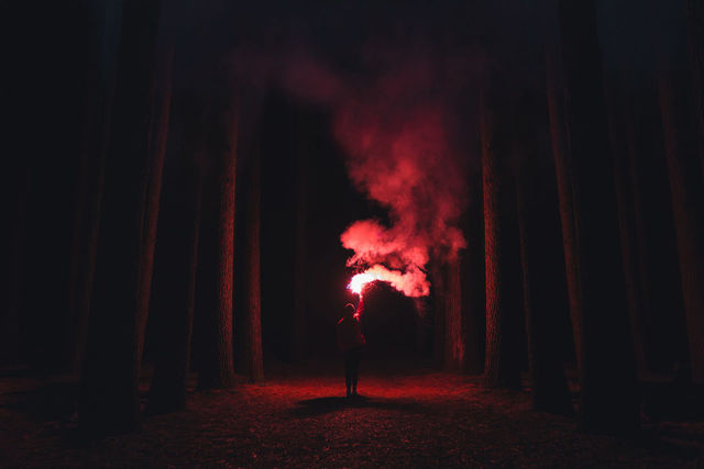 Man standing in illuminated fire at night | ID: 100261300